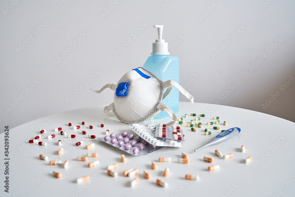 Breathing mask with antibacterial gel and tablets with a thermometer on ...