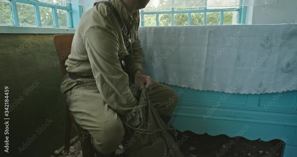 Soldier taking break from war in old house. Tilt up view of adult ...
