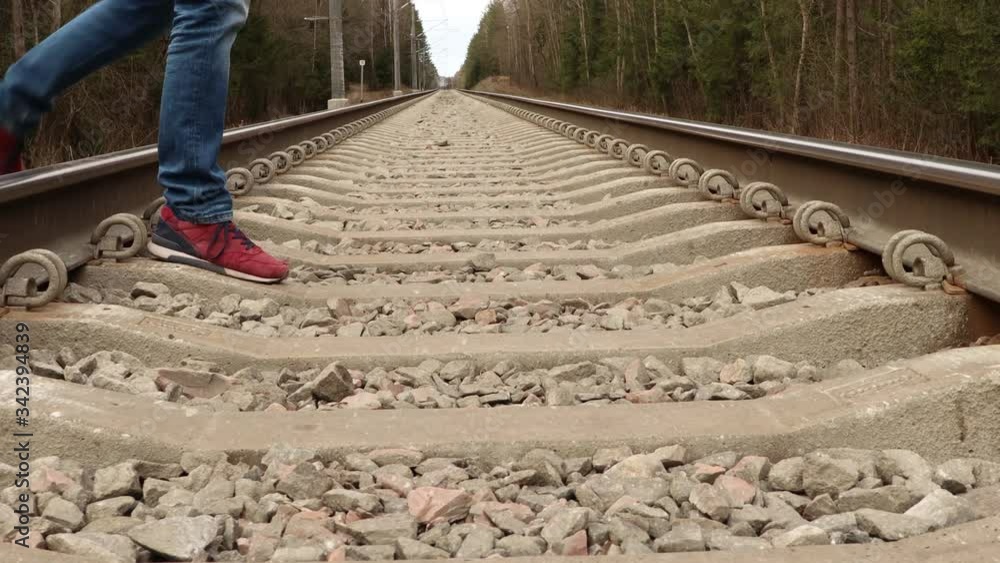 A man goes over the rails. A man crosses the railways of a train near ...