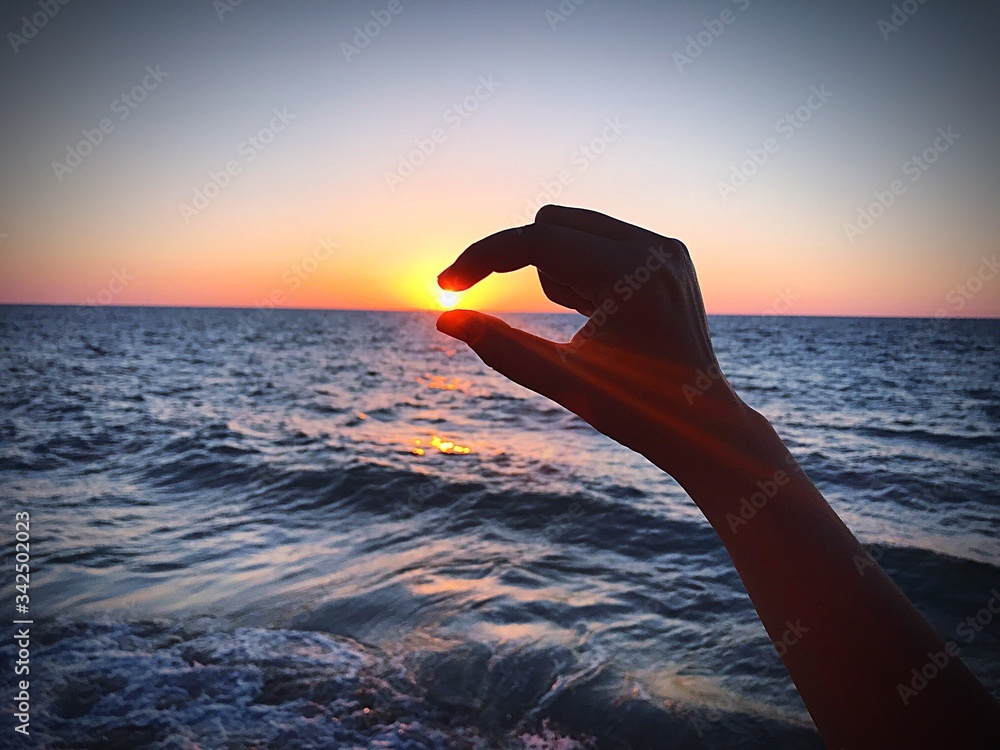Optical Illusion Of Hand Holding Sun During Sunset Stock Photo | Adobe ...