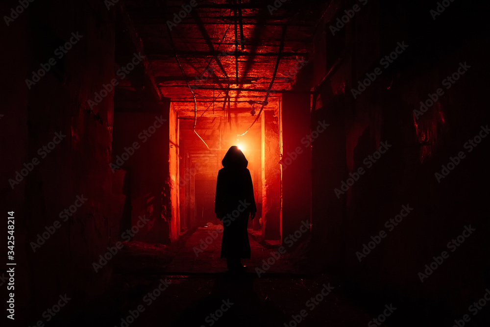 Creepy silhouette in the dark red illuminated abandoned building ...