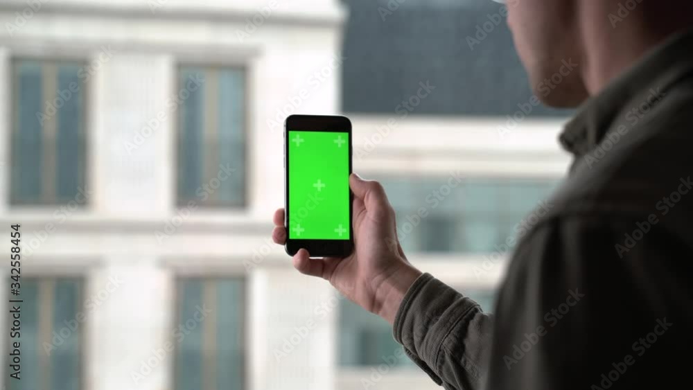 Hands use touch holding a mobile telephone with a vertical green screen in tram chroma key ...