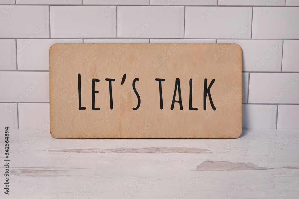 Let's talk message written on a rustic wood board leaning on a white ...