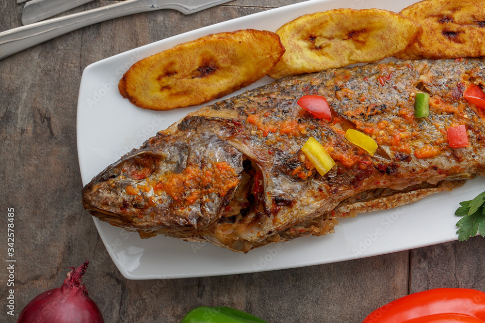 Grilled fish curry with plantain and salad. African national dish ...