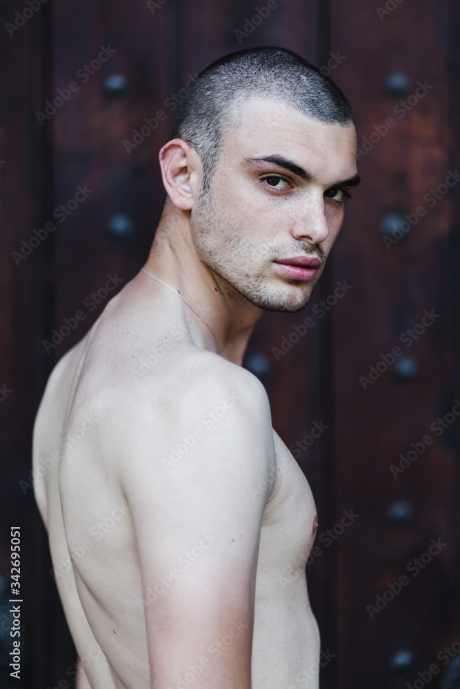 Portrait Of Shirtless Male Model Standing Against Door Stock Photo ...