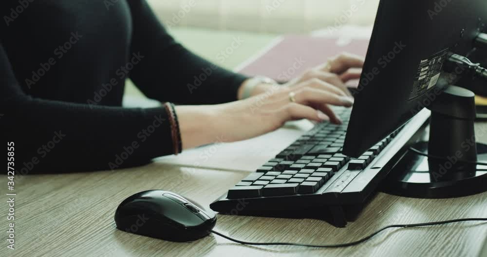 woman working in front of monitor. closeup of hands behind the keyboard ...