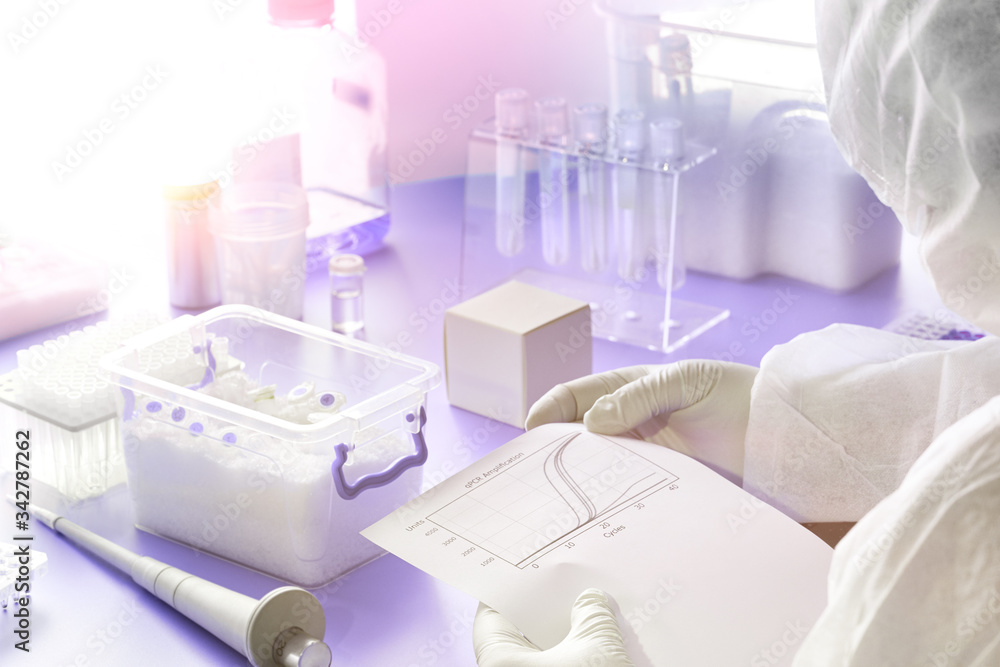 SARS-COV-2 pcr diagnostics kit. Epidemiologist in protective suit, mask and glasses mixes ...