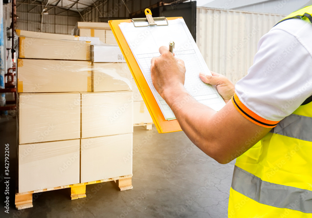 Worker Holds a Clipboard Controlling the Loading of Cargo into Shipping ...