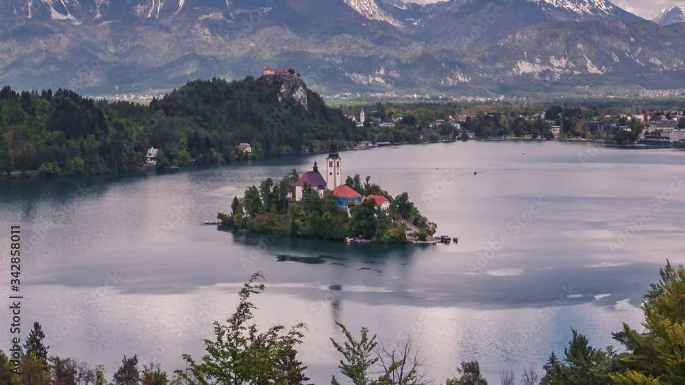 Zoom out time lapse through forest view of spring lake Bled island ...