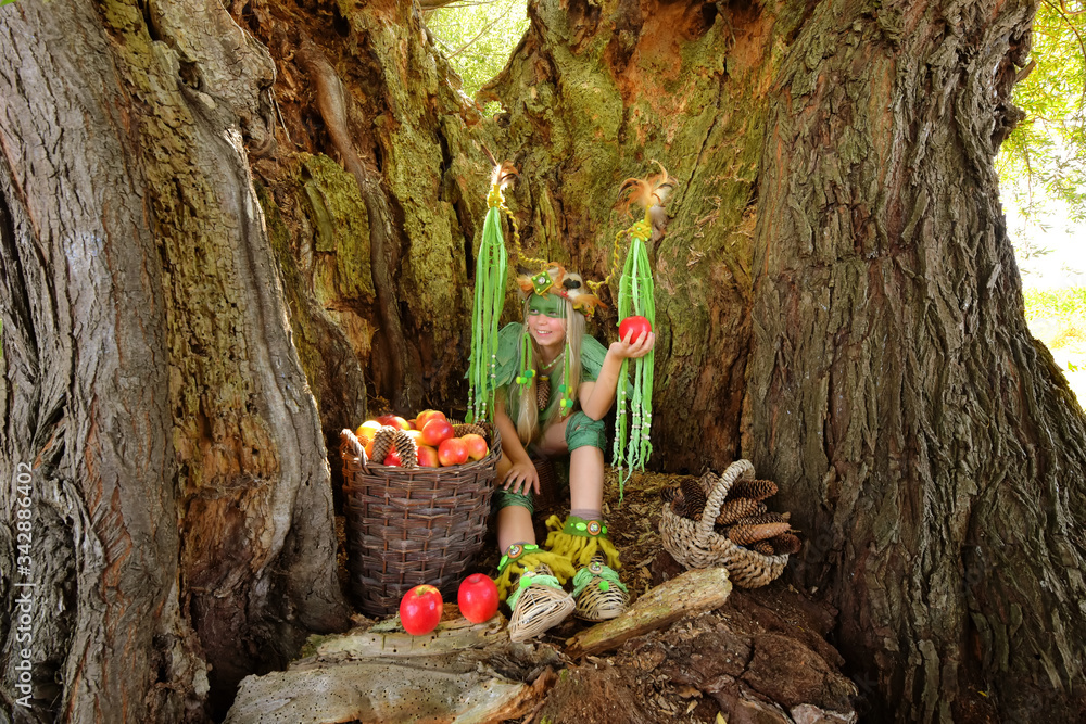 A young girl is dressed up as a fairy. She is seen inside a hollow tree ...