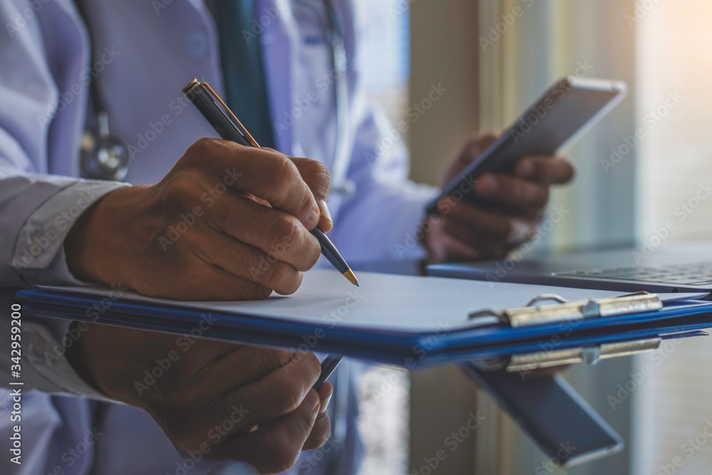 Male doctor hand using mobile phone and writing note on data chart ...