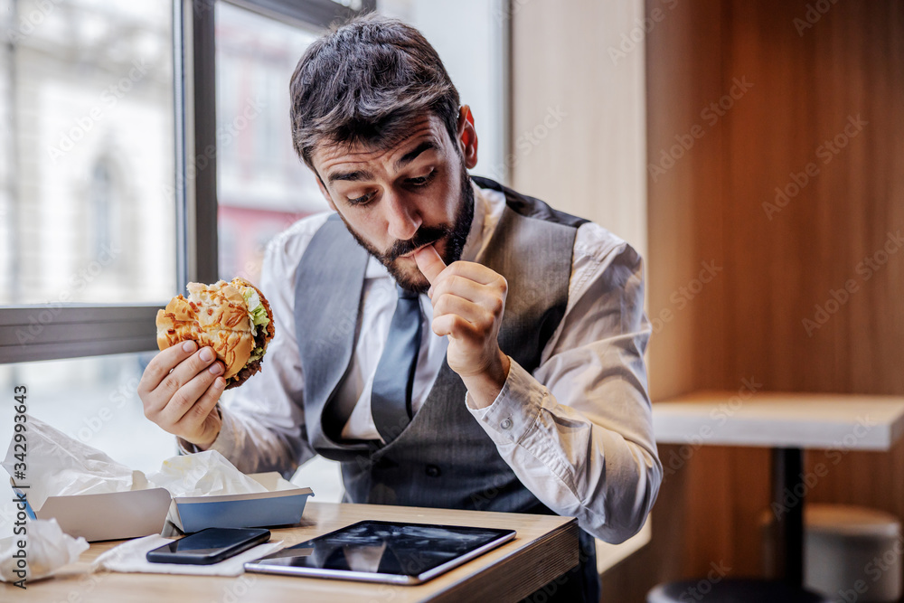 Hungry man in suit sitting in fast food restaurant on lunch break ...