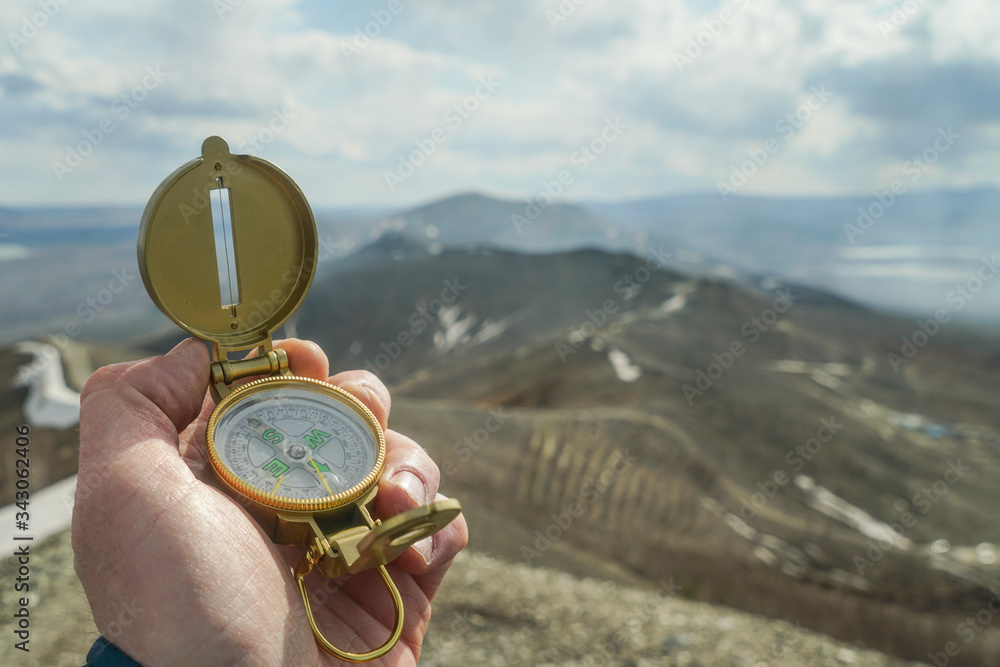 Old gold compass in hand on a background of mountains of nature. Travel ...