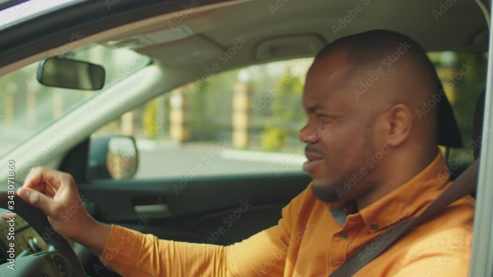 Angry african male driver hitting steering wheel with fist while ...