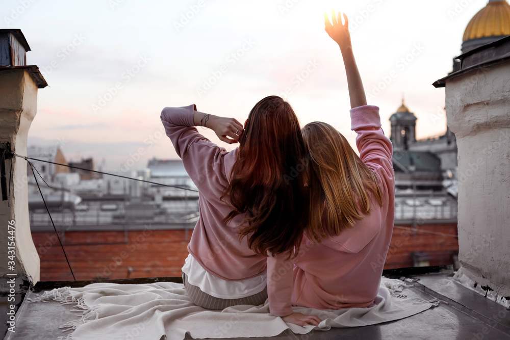 Two girls are sitting back view on the roof Stock Photo | Adobe Stock