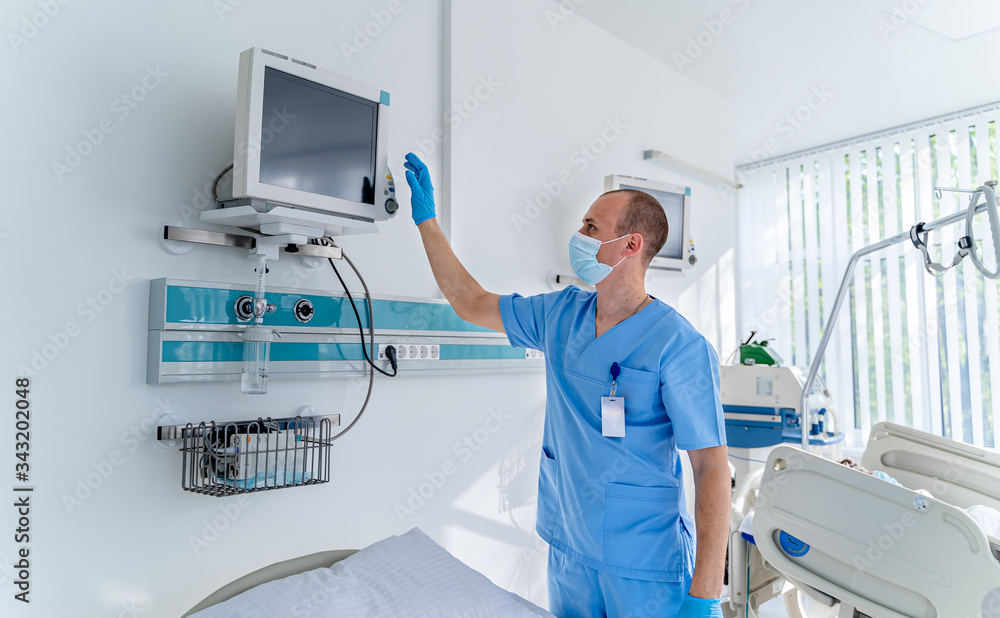 Doctor in blue medical clothes and mask is looking at the screen with ...