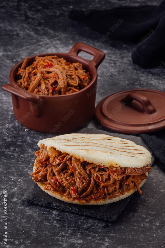 Arepa stuffed with shredded meat on a dark background. (Arepa con carne ...