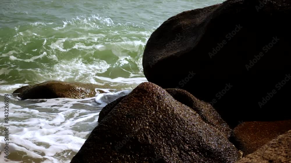 Ocean wave beats of the big rocks standing in the ocean. Closeup of big ...