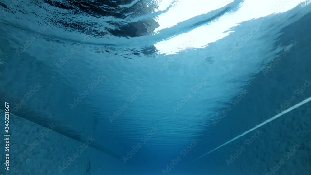Young man in swimsuit swims one way in the waterpool freestyle. Slow ...