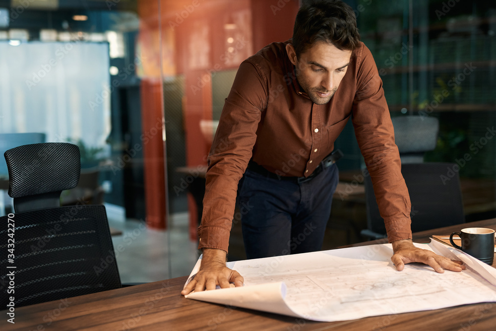 Architect leaning over an office table and reading blueprints Stock ...