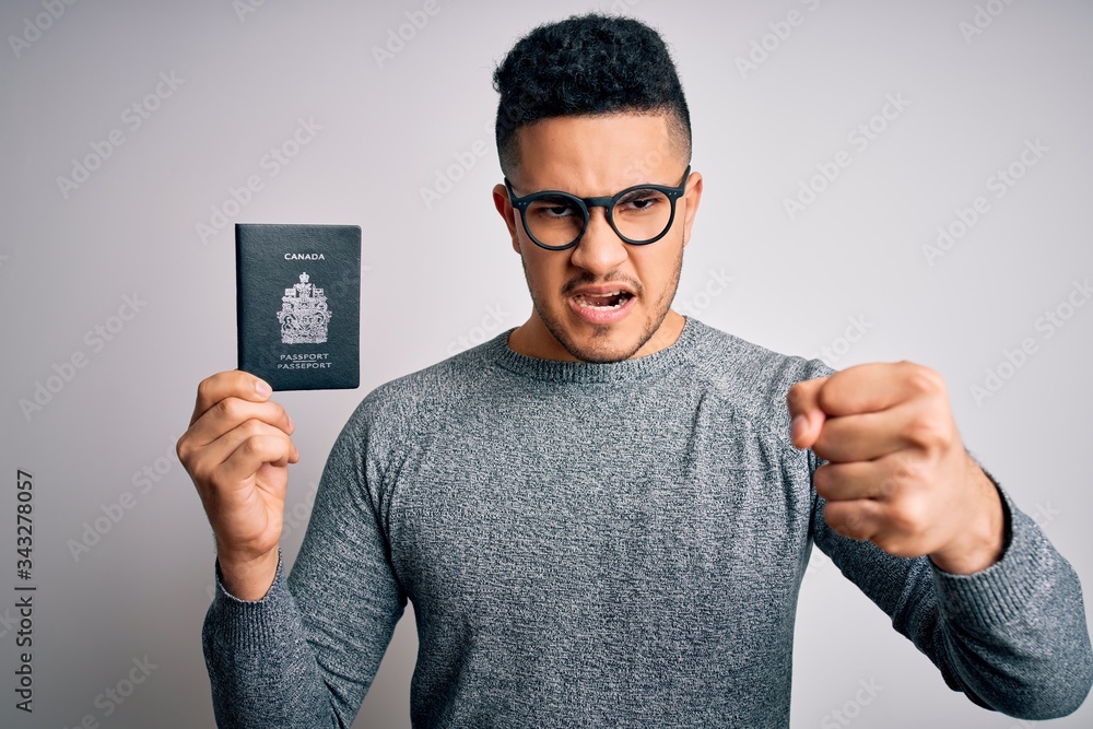Young handsome tourist man on vacation wearing glasses holding Canada ...