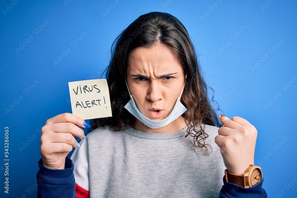Young beautiful woman with curly hair wearing mask holding reminder ...