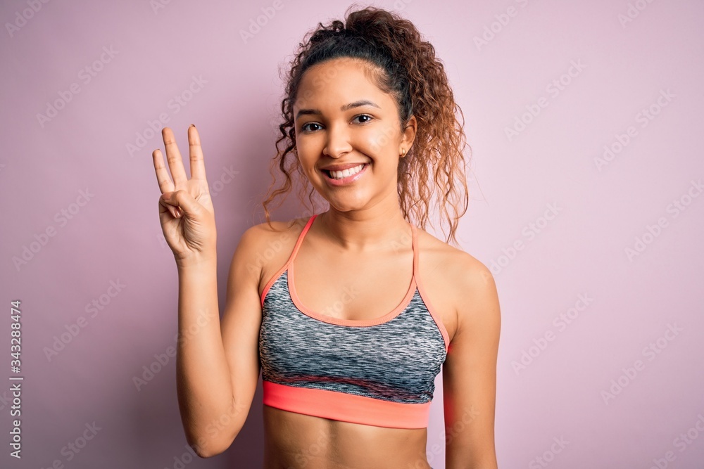 Beautiful sportswoman with curly hair doing sport wearing sportswear ...