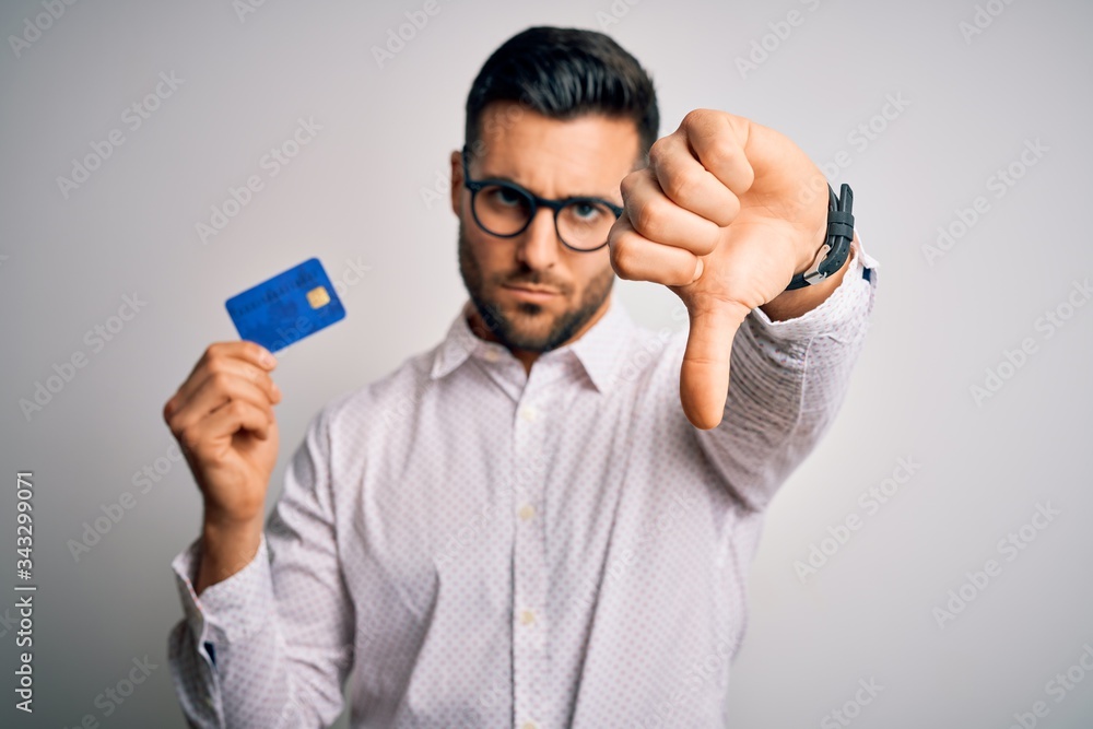 Young business man holding credit card over isolated background with ...