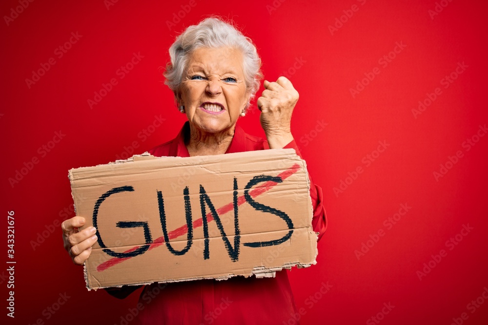 Senior beautiful grey-haired woman holding banner with prohibited guns ...