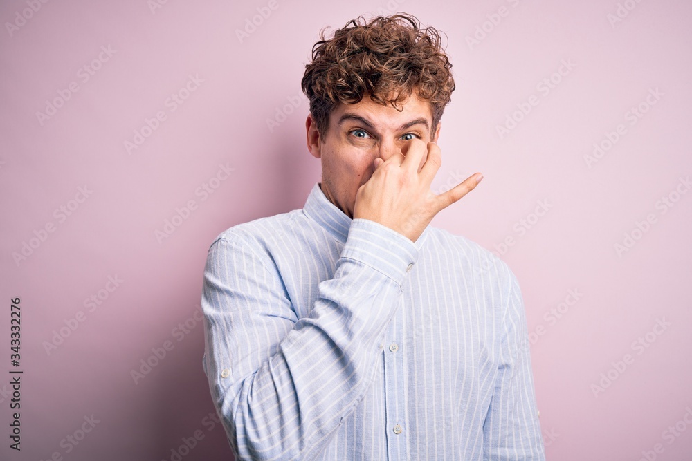 Young blond handsome man with curly hair wearing striped shirt over ...