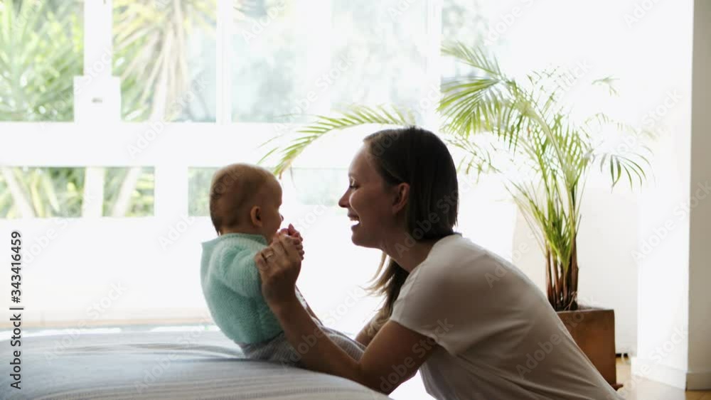 Positive excited mom helping baby daughter to sit up. New mother ...