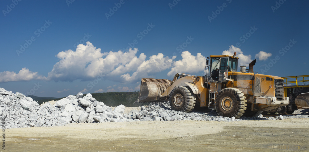 Wheel front-end loader in a quarry on the background of the wreckage of ...