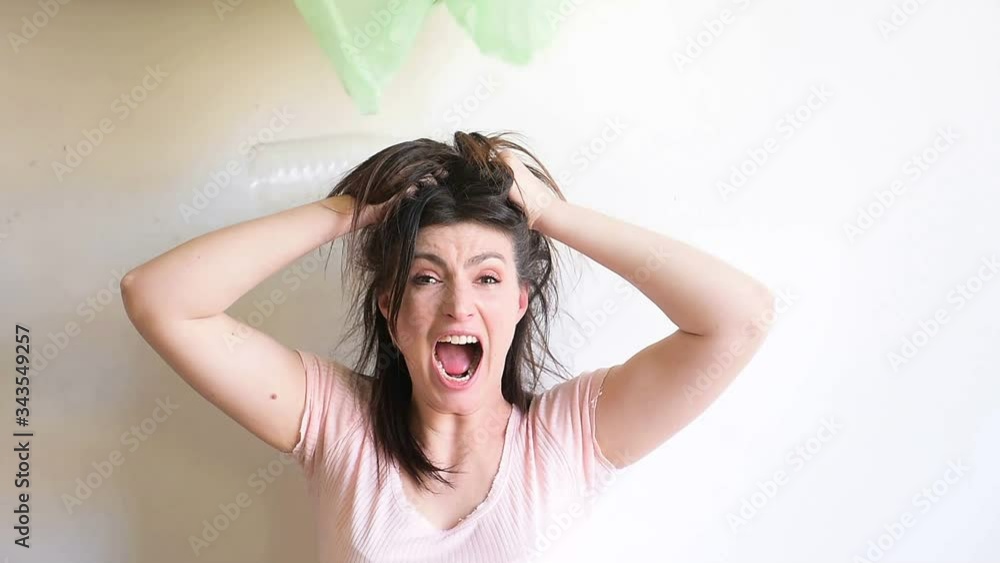 Empty plastic bottles are pouring on the girl’s head. The girl with her ...