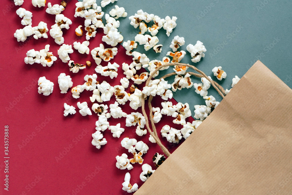 Popcorn dropped and scattered from paper craft bag on maroon and gray ...