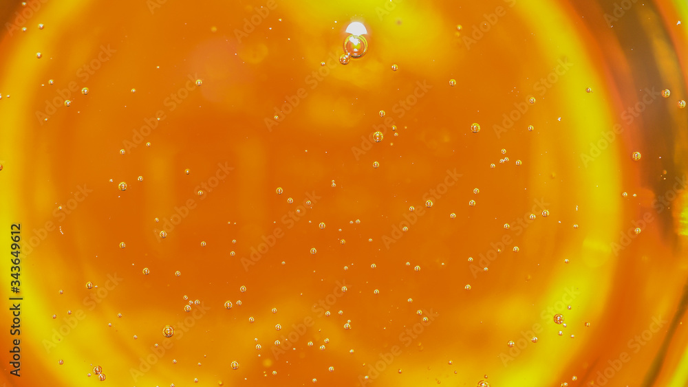 Macro close up floating orange syrup bubbles background. Corn syrup ...