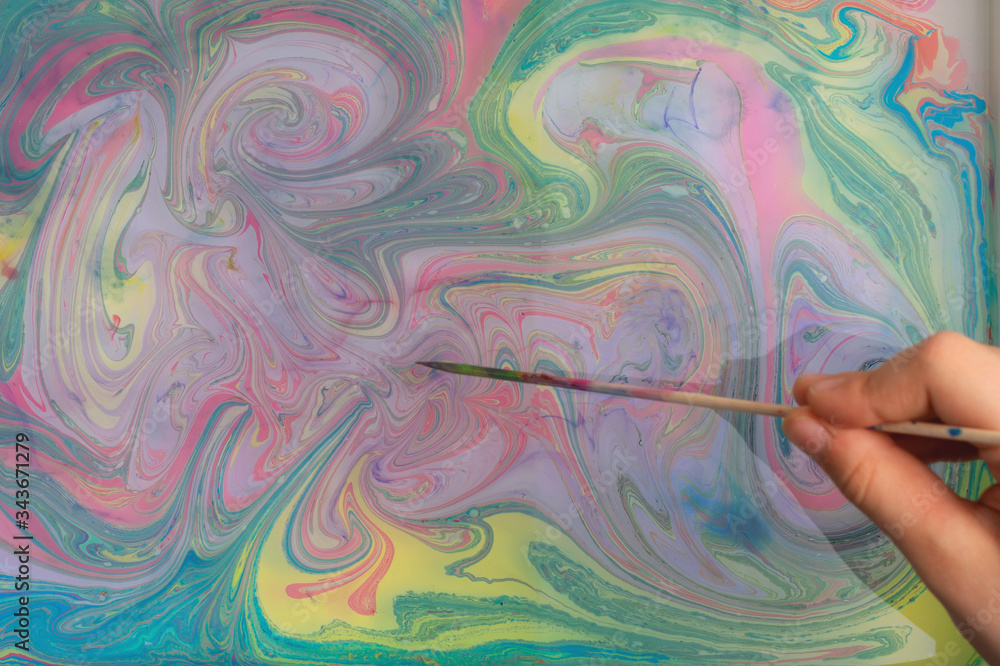 Drawing on the surface of the water. Paper marbling technique. Child's ...