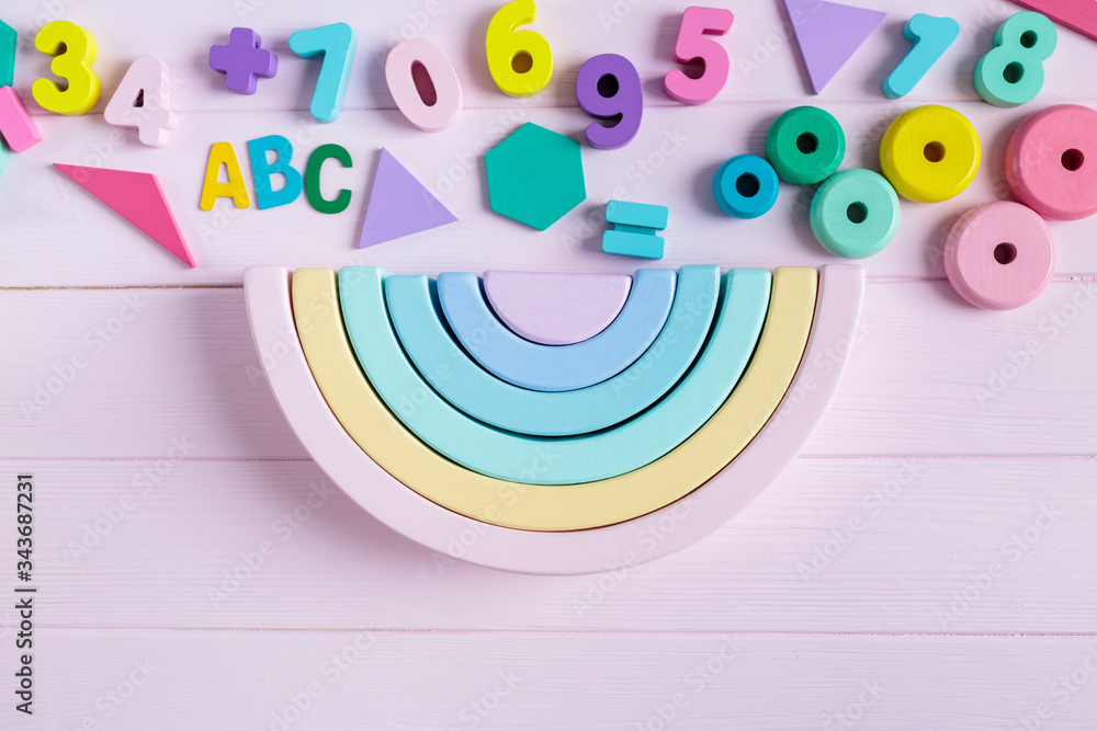 Wooden toy rainbow, pastel color arc on light pink background. Natural ...