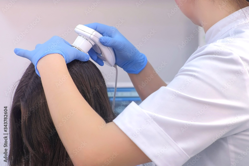 Doctor trichologist examines woman patient's hairs using trichoscope in ...