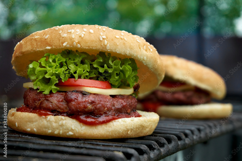 Tasteful white sesame bun burger standing on metal grill surface ...