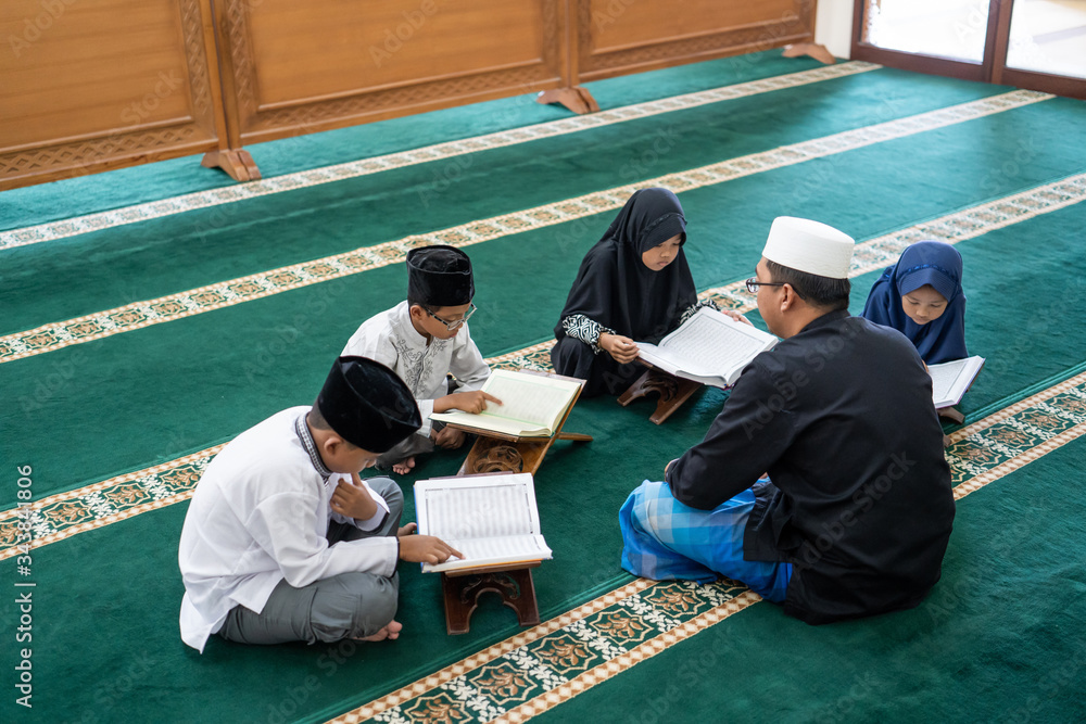 teacher is teaching muslim kid how to read holy quran in the mosque ...