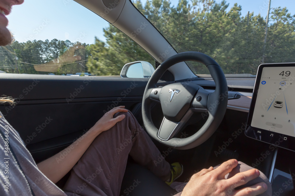 Person driving a Tesla Model 3 on autopilot Stock Photo | Adobe Stock