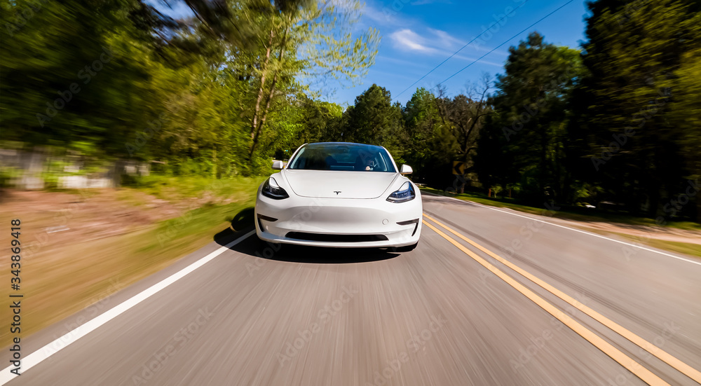 A new Tesla Model 3 all electric car driving down the road Stock Photo ...