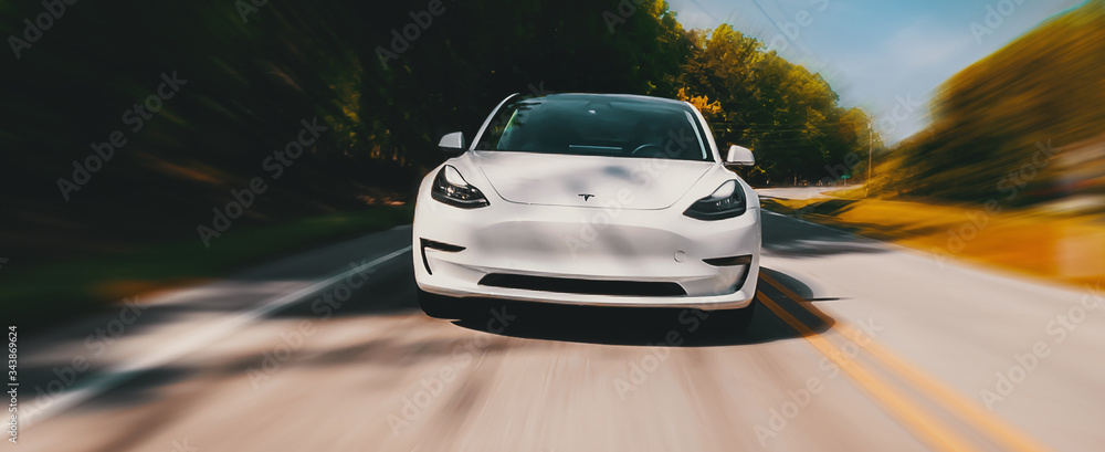 A new Tesla Model 3 all electric car driving down the road Stock Photo ...