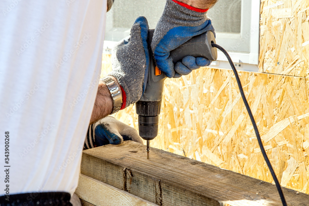 Carpenter using an electric screwdriver screwing wood screw into wood ...