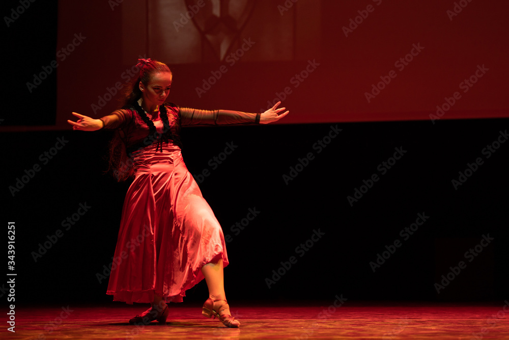 Dancer in a red dress dancing Spanish flamenco on the stage in the ...
