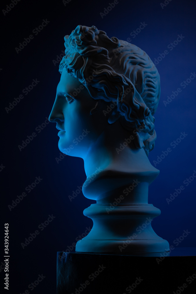 Statue of a bust of Apollo's head in blue local light on a yellow ...
