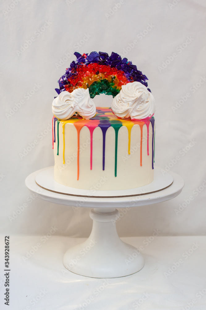 LGBT rainbow cake with melted chocolate and caramel rainbow on white ...