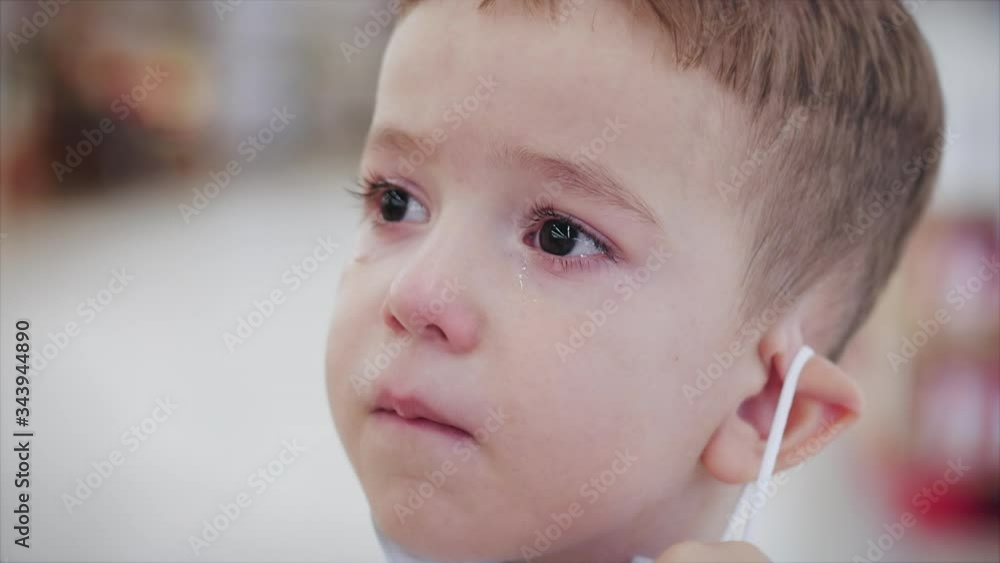 Portrait of an upset tearful cute little baby boy in a mask from ...