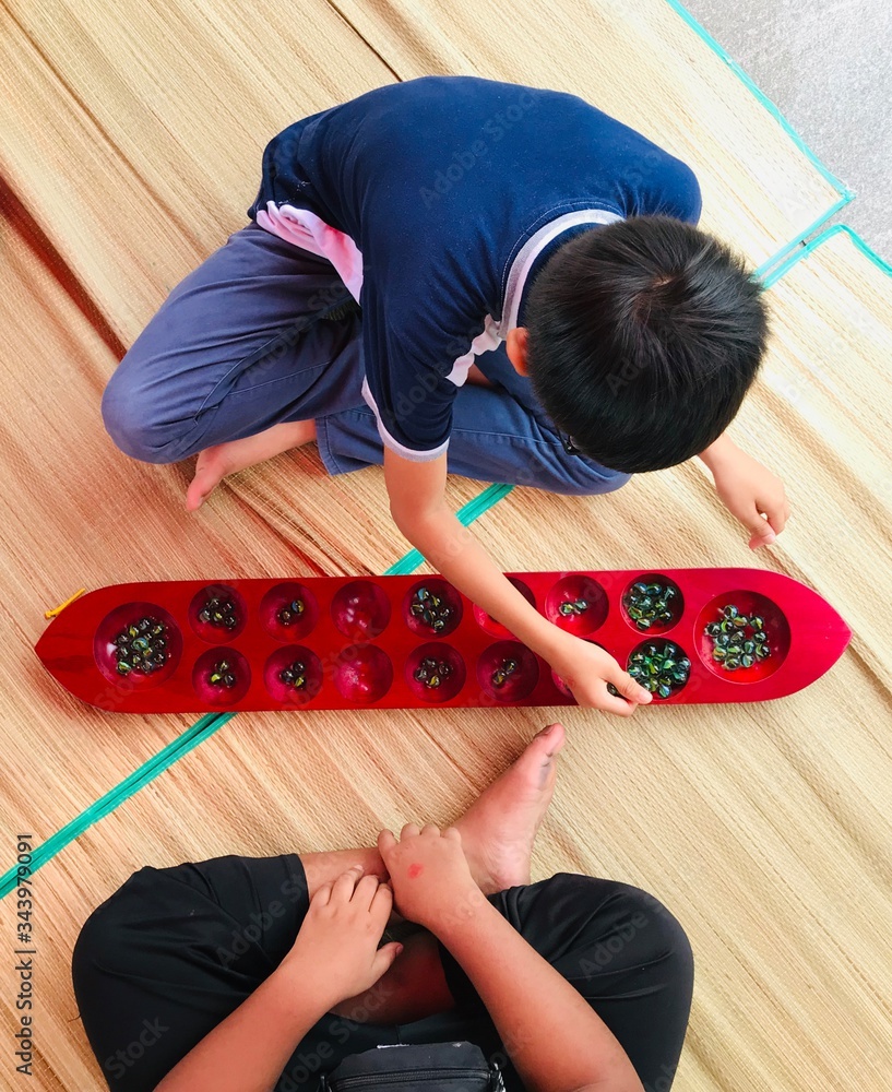 kids playing congkak (Malay traditional games) Stock Photo | Adobe Stock