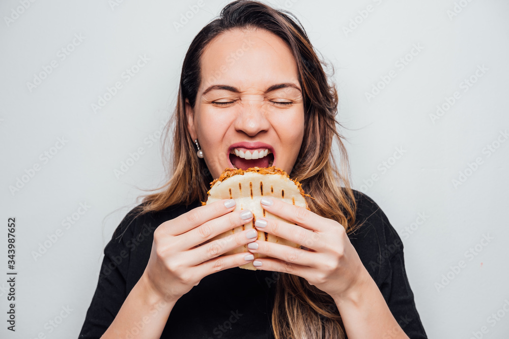Portrait of girl eating an arepa of shredded meat. Typical Latin ...